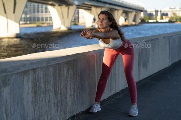 Fit young athletic female extends her arms in front of her and performs ...