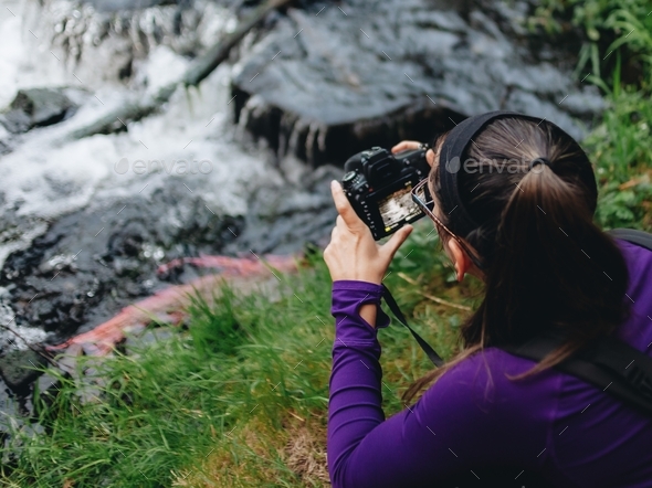Young millennial girl taking photos of a running stream Stock Photo by ...
