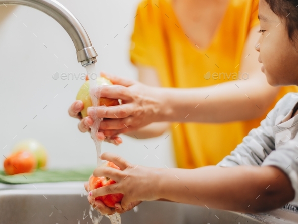 Mother and daughter washing apples in preparation for the making of ...