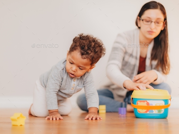Mother at home playing with baby son, sorting game, milestone ...
