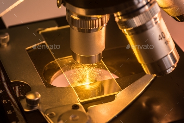 Close up of compound microscope lenses, slide on stage of microscope ...