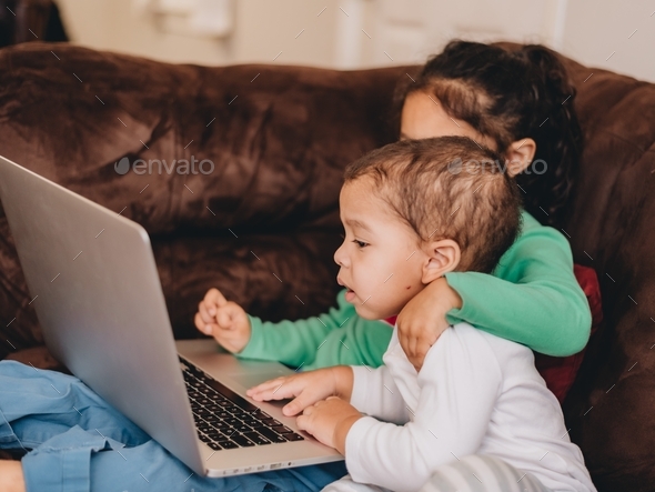 Diverse brother and sister at home using a laptop computer, big sister ...