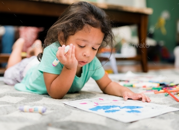 Diverse pre school girl at home playing with colored pencils and ...