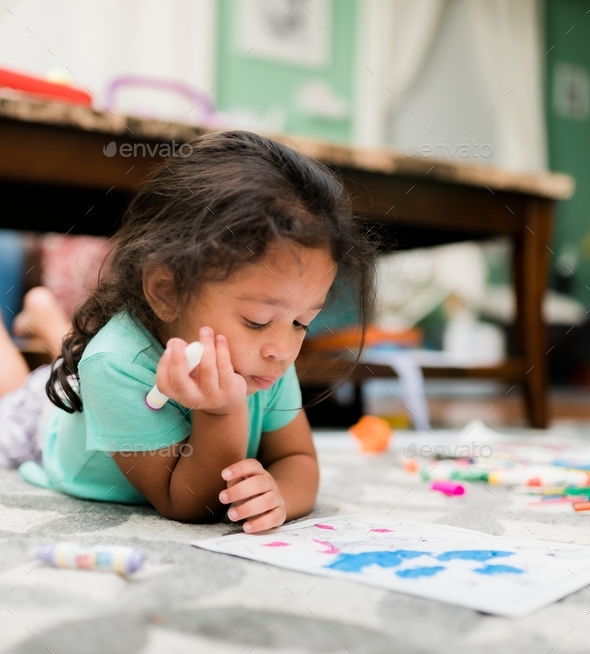 Diverse pre school girl at home playing with colored pencils and ...