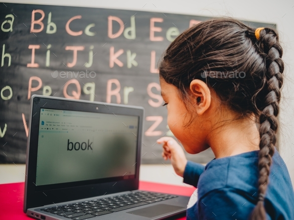 pre-k girl at home on computer doing online schooling or e-learning ...