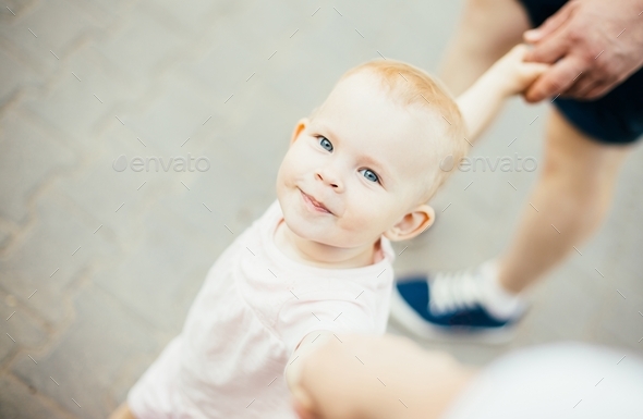 Cute baby walking on street with her parents Stock Photo by Polinalebed