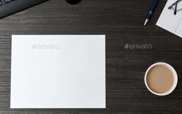 Blank paper laying flat on dark desk next to cup of copy ready for mock ...