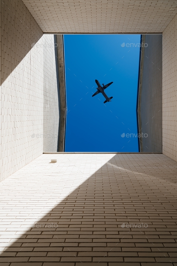 Plane flying above courtyard of modern architecture brick building ...