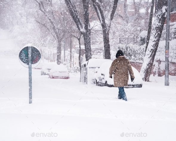 People walking on a city street covered in snow during heavy snowfall ...
