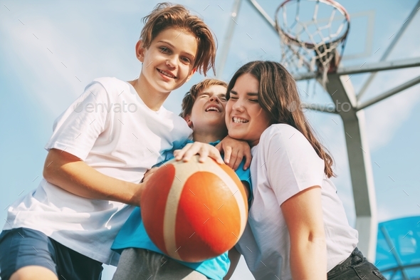 Happy friends are standing hugging on the basketball court and having ...