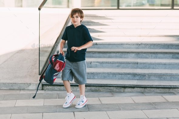A cute boy with a backpack in one hand and a basketball in the other ...