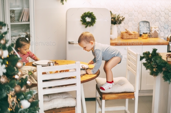 Cute little children play at the table set for dinner on Christmas and ...