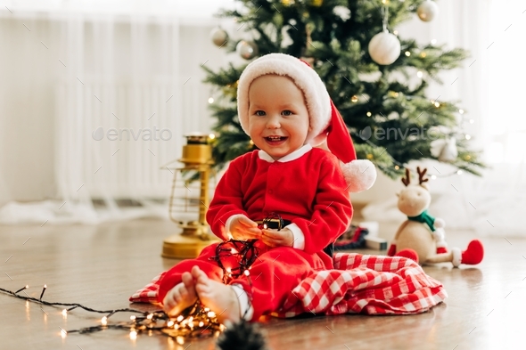A cheerful boy in a New Year's costume sits on the floor near the ...