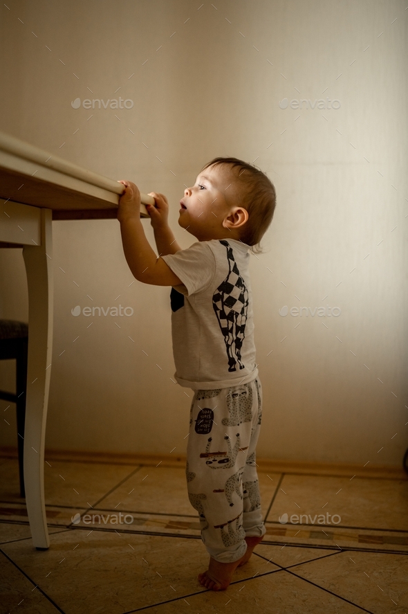 the kid is trying to look at something on a high table Stock Photo by ...
