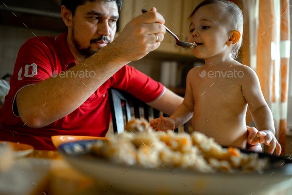 Dad feeds his son. The family is having dinner at home Stock Photo by ...