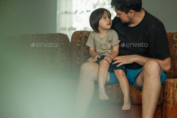 The son sits on his father's lap, dad tells his son a fairy tale. Dad ...