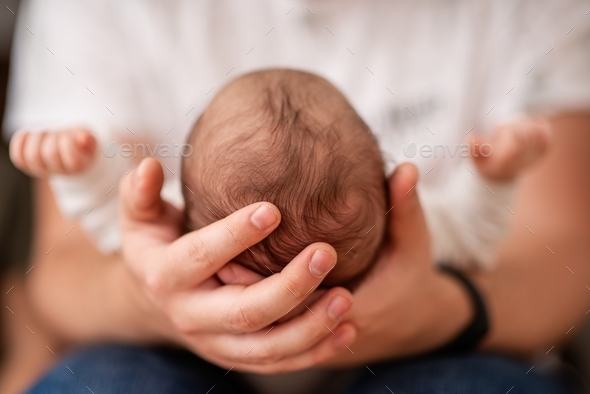A tender, fragile baby newborn lies in the big courageous hands of the ...