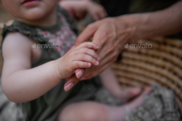 Close up of mother's hand hugging baby daughter's fingers. Maternal ...