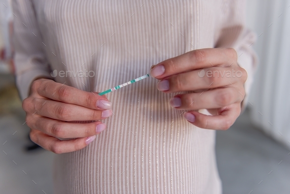 Pregnant young woman is holding paper pregnancy test, two stripes ...