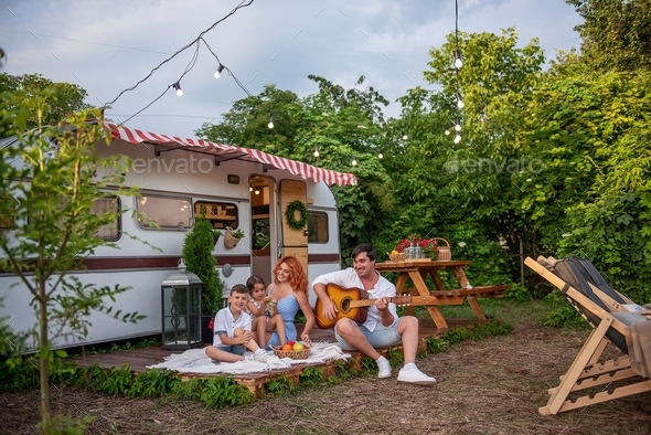Young father plays the guitar, red-haired mother with children sing ...