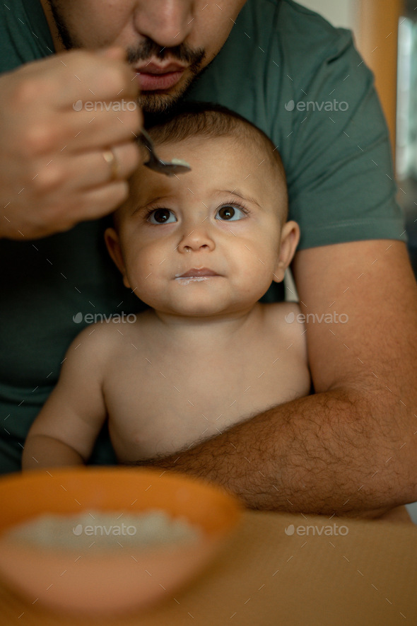 Dad feeds his son porridge. The family has breakfast Stock Photo by ...