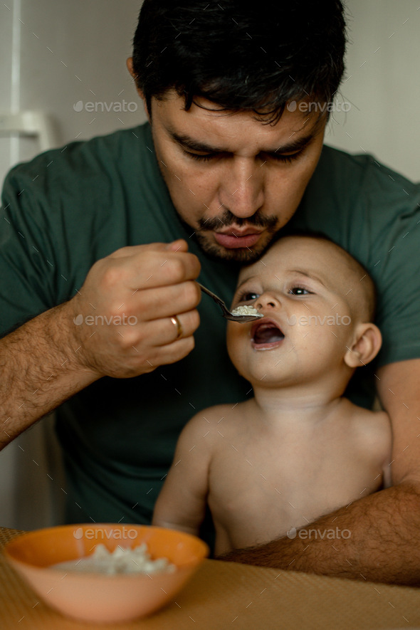 Dad feeds his son porridge. The family has breakfast Stock Photo by ...