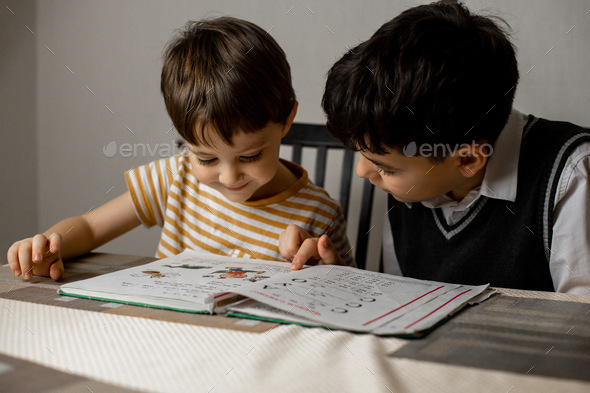 The older brother teaches his little brother to read Stock Photo by ...