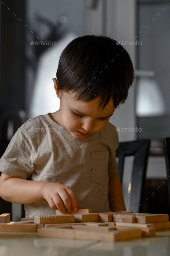 A little boy builds a tower of wooden sticks Stock Photo by nastuffa