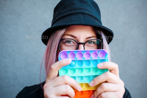 Young Girl Holding pink Pop It Fidget Toy in hands. Teen Playing Stock ...