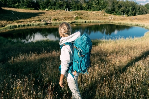 Back view of a woman hiker against the backdrop of a mountain lake and ...