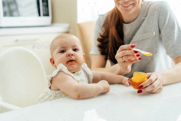 the parent feeds the baby with a spoonful of prepared vegetable puree ...