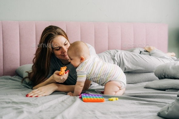 Mom plays with baby in bed, baby learns to crawl, family fun Stock ...