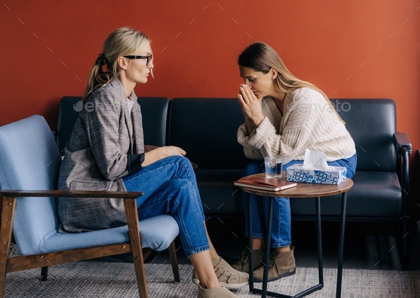 Crying depressed female client sitting on couch in therapist's workshop ...