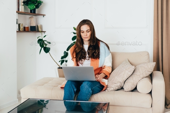 Business busy woman at home on the couch working online in a laptop ...