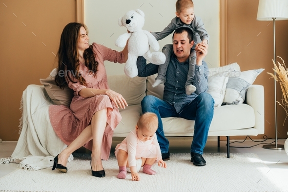 Family portrait of parents with small children sitting on the couch and ...
