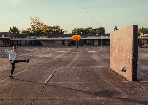 A boy is kicking a ball of the wall on the school yard Stock Photo by ...