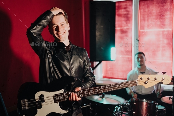 Young guys playing on electric guitar and drums in a authentic studio ...