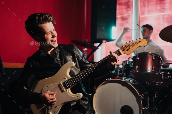 Young man singing and playing on electric guitar in a authentic studio ...