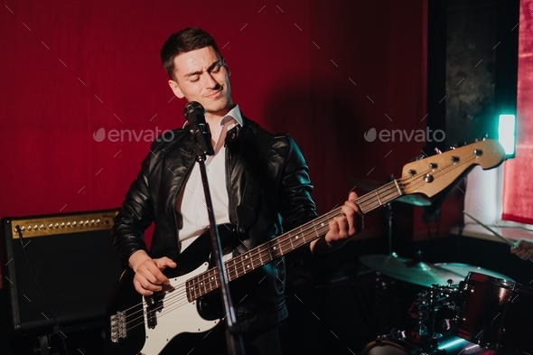 Young man singing and playing on electric guitar in a authentic studio ...