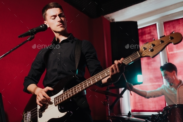 Young man singing and playing on electric guitar in a authentic studio ...