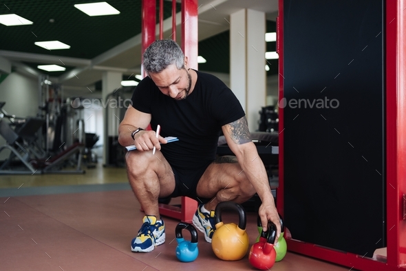 Coach making sport plan routine in the gym writing down the exercises ...