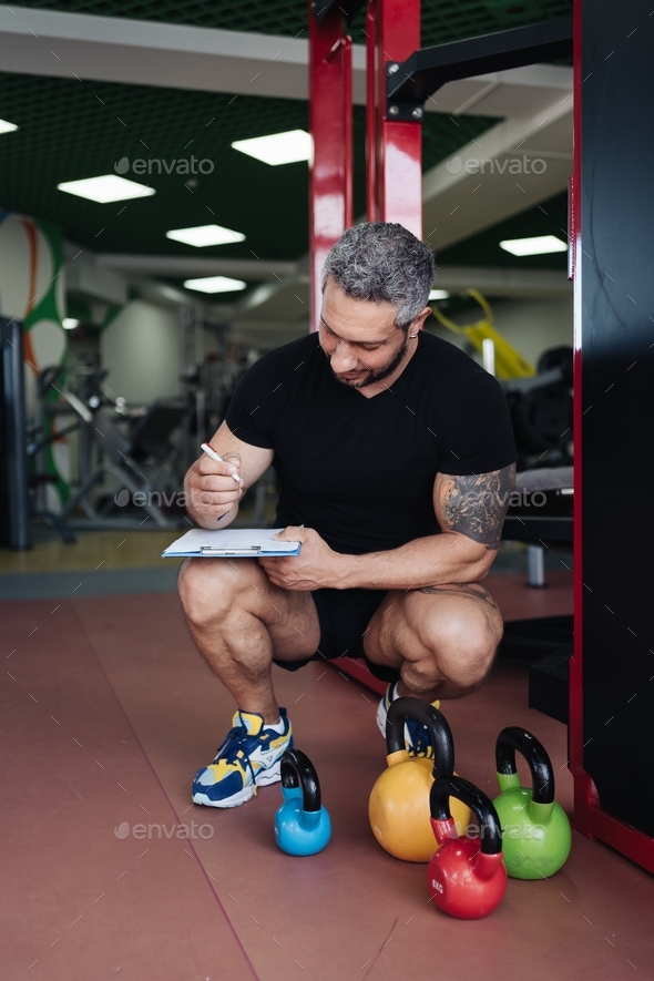 Coach making sport plan routine in the gym writing down the exercises ...