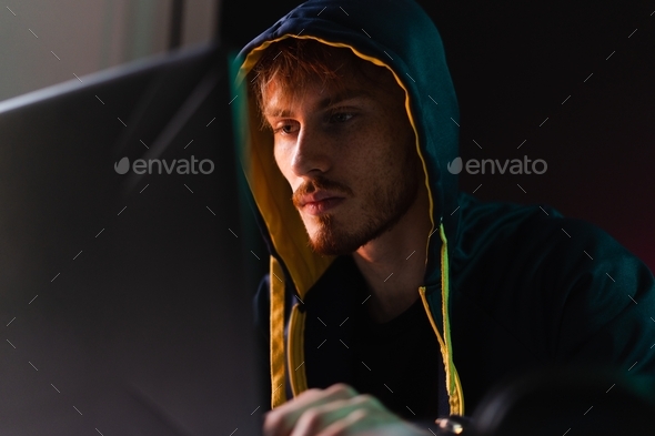 Hacker it genius using laptop writing code wearing hood on head. Cyber ...