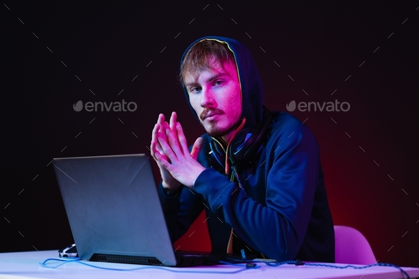 Hacker it genius using laptop writing code wearing hood on head. Cyber ...