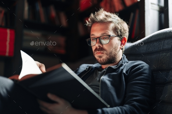 Adult college student reading a book in the university library ...
