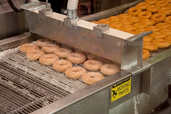 Donuts factory machine. Glazing of fresh made donuts Stock Photo by ...