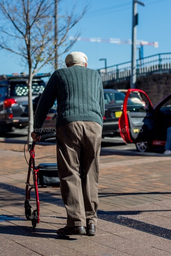 Old man with the walker walking along the street Stock Photo by Daria_Nipot
