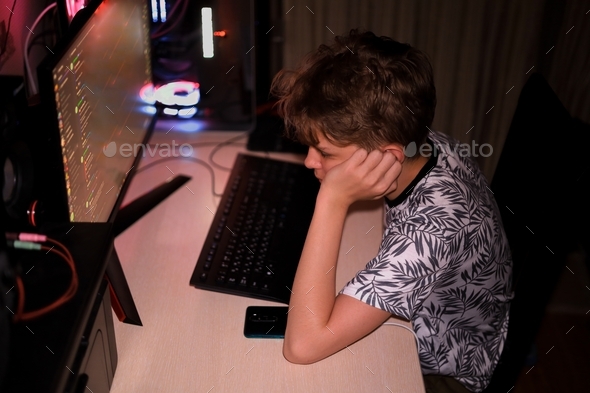 Handsome teenage boy playing computer in the dark using modern ...