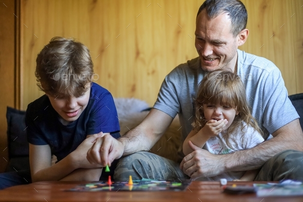 Family - Dad and his children of different ages play board games at ...