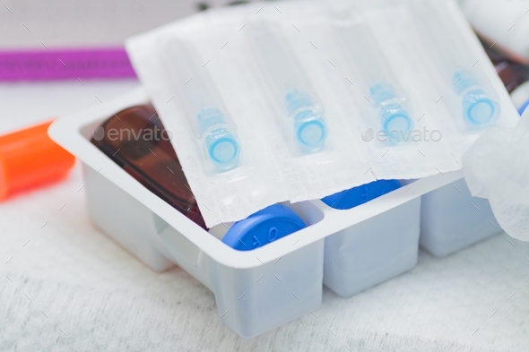 Medical bottles and ampoules with syringe needles in a pack. Injection ...